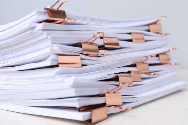 Binder clips with sheets of paper on table, closeup - Budget and the Bees